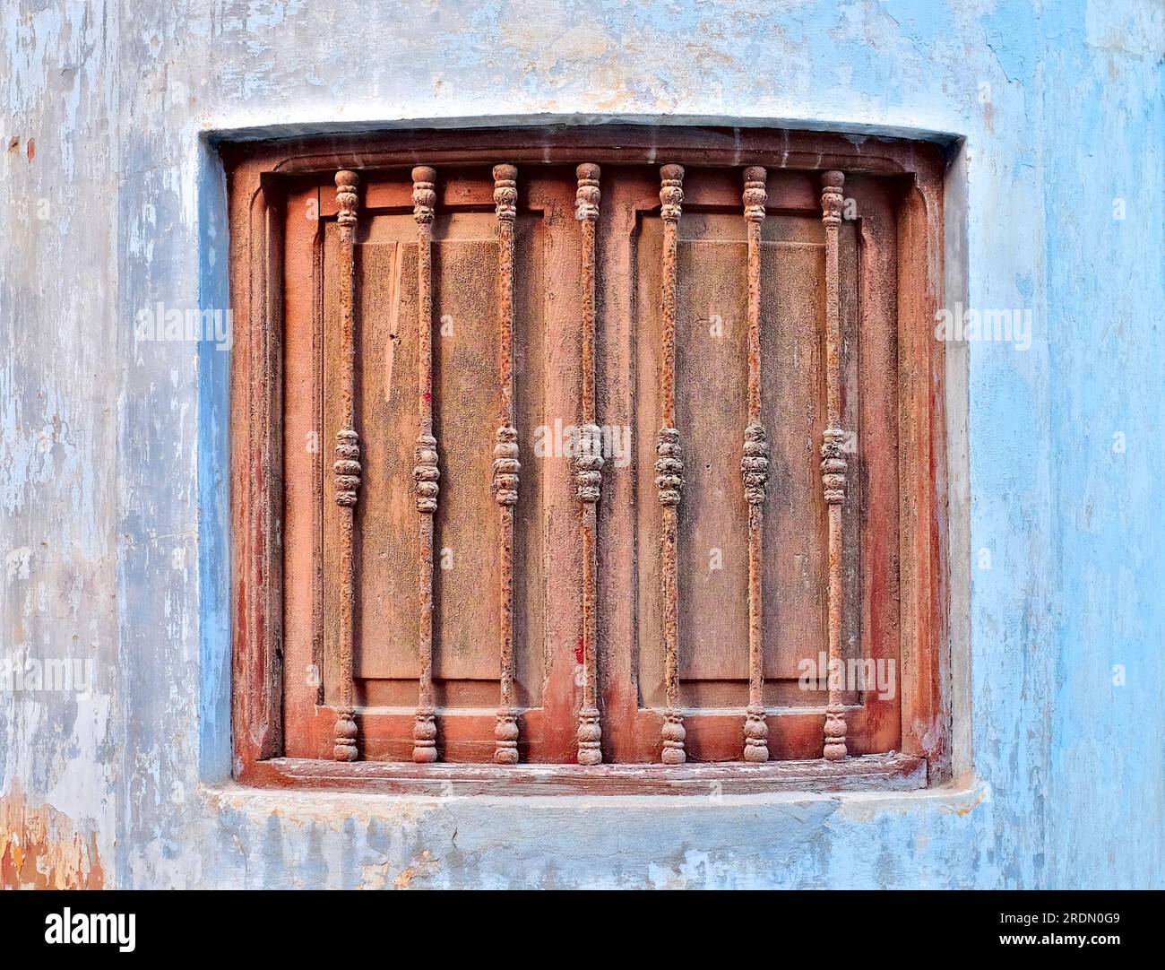 Barred closed window in a pastel blue wall, old town architecture ...