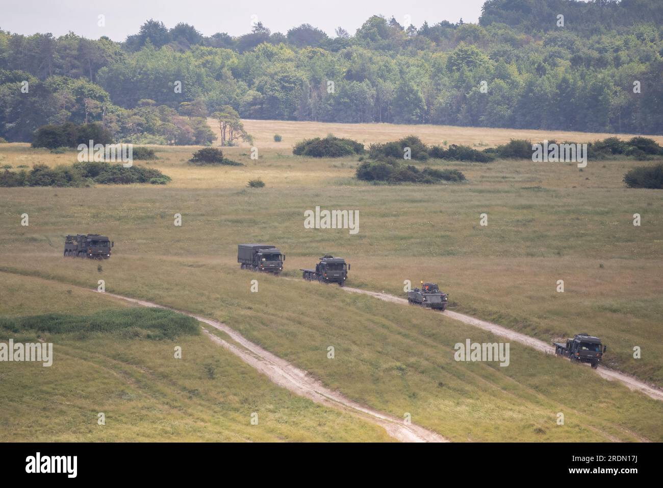 a convoy of British army vehicles moving across countryside on a ...