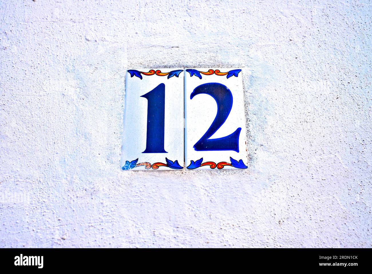 Simple number 12, twelve, plain floral tiles on a white wall with ...