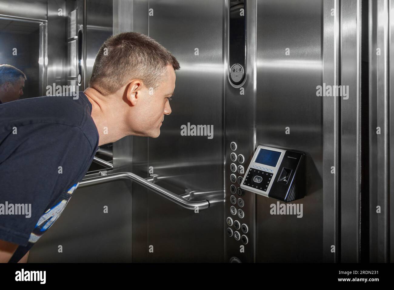 A man shows his face to a fingerprint access control terminal with a ...