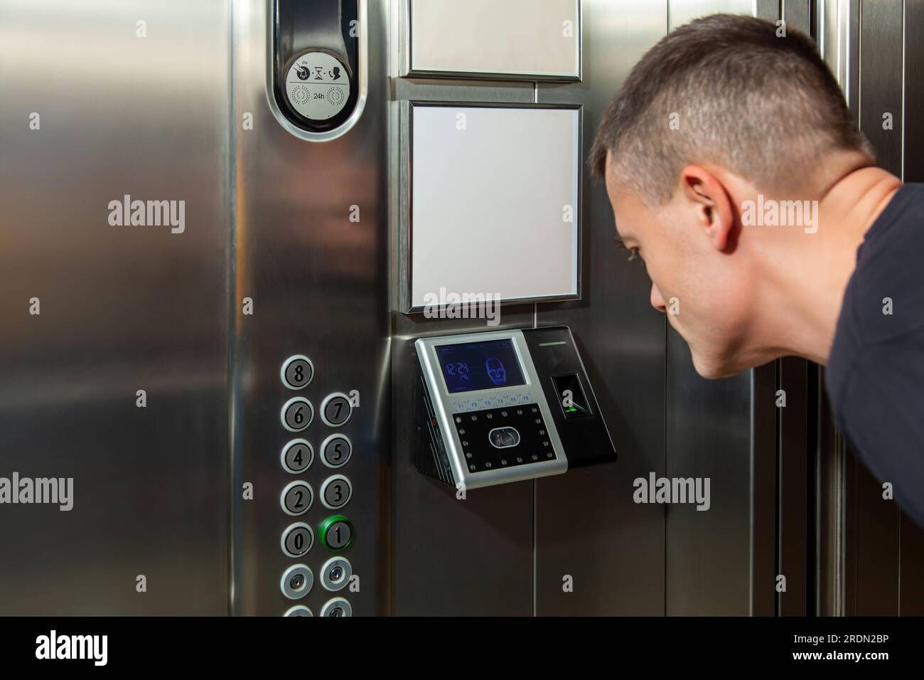 A man shows his face to a fingerprint access control terminal with a ...