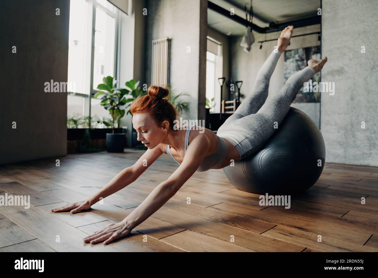 Slim woman stretches on exercise pilates ball in fitness studio or gym ...