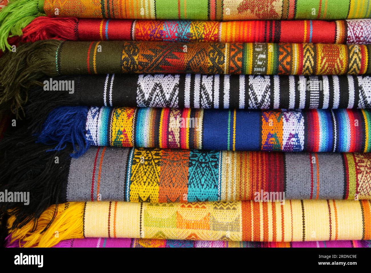 Brightly colored folded traditional fabric for sale at Otavalo market ...