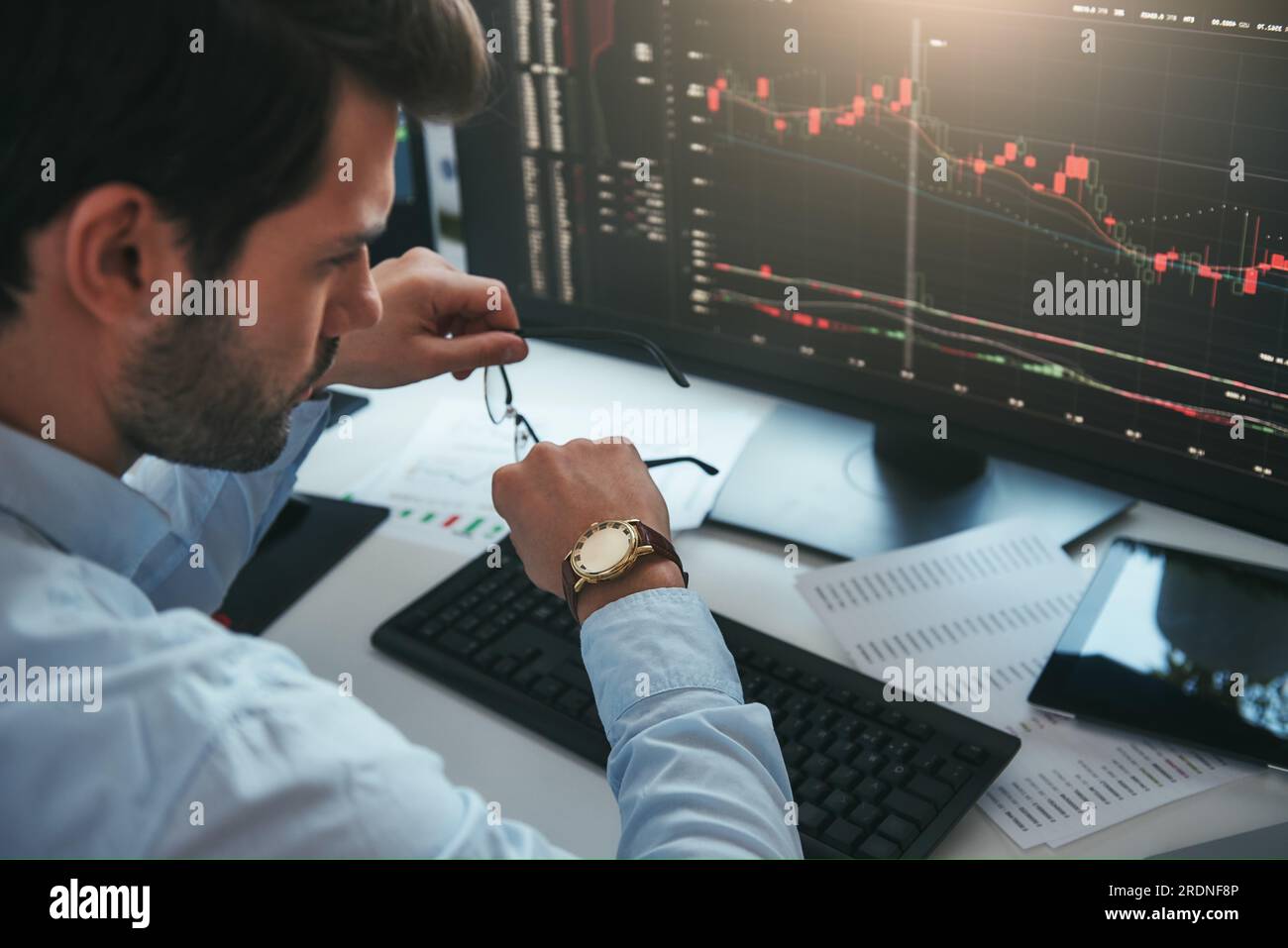 Time to trade. Bearded male trader looking at watch on his hand while ...