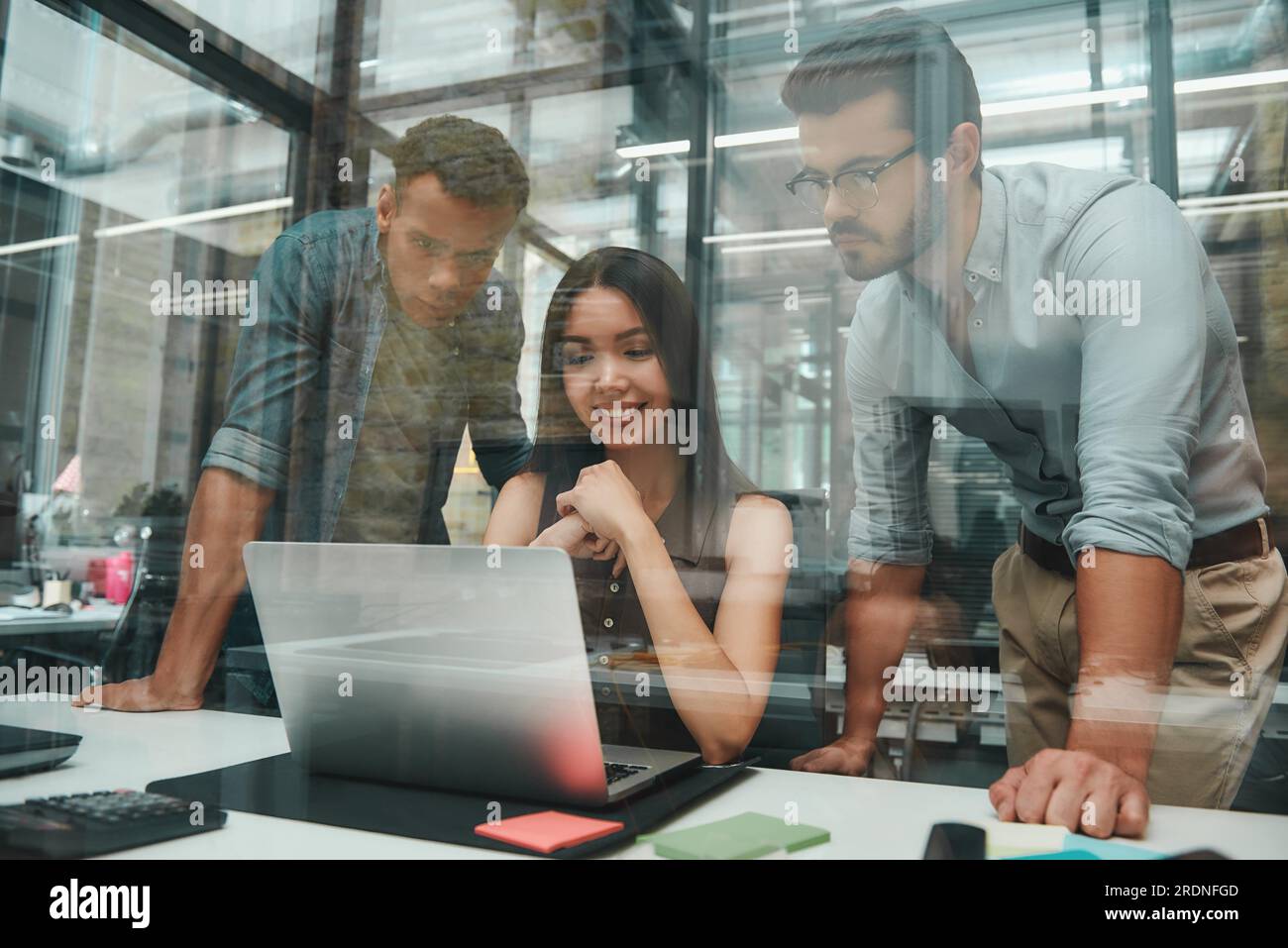 Busy day. Group of three young employees looking at screen of laptop ...