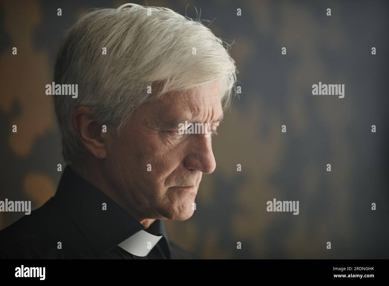 Close up side view portrait of white haired senior man in clerical ...
