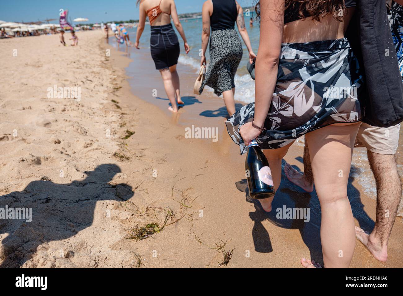 Young people walking on beach with champagne Stock Photo - Alamy
