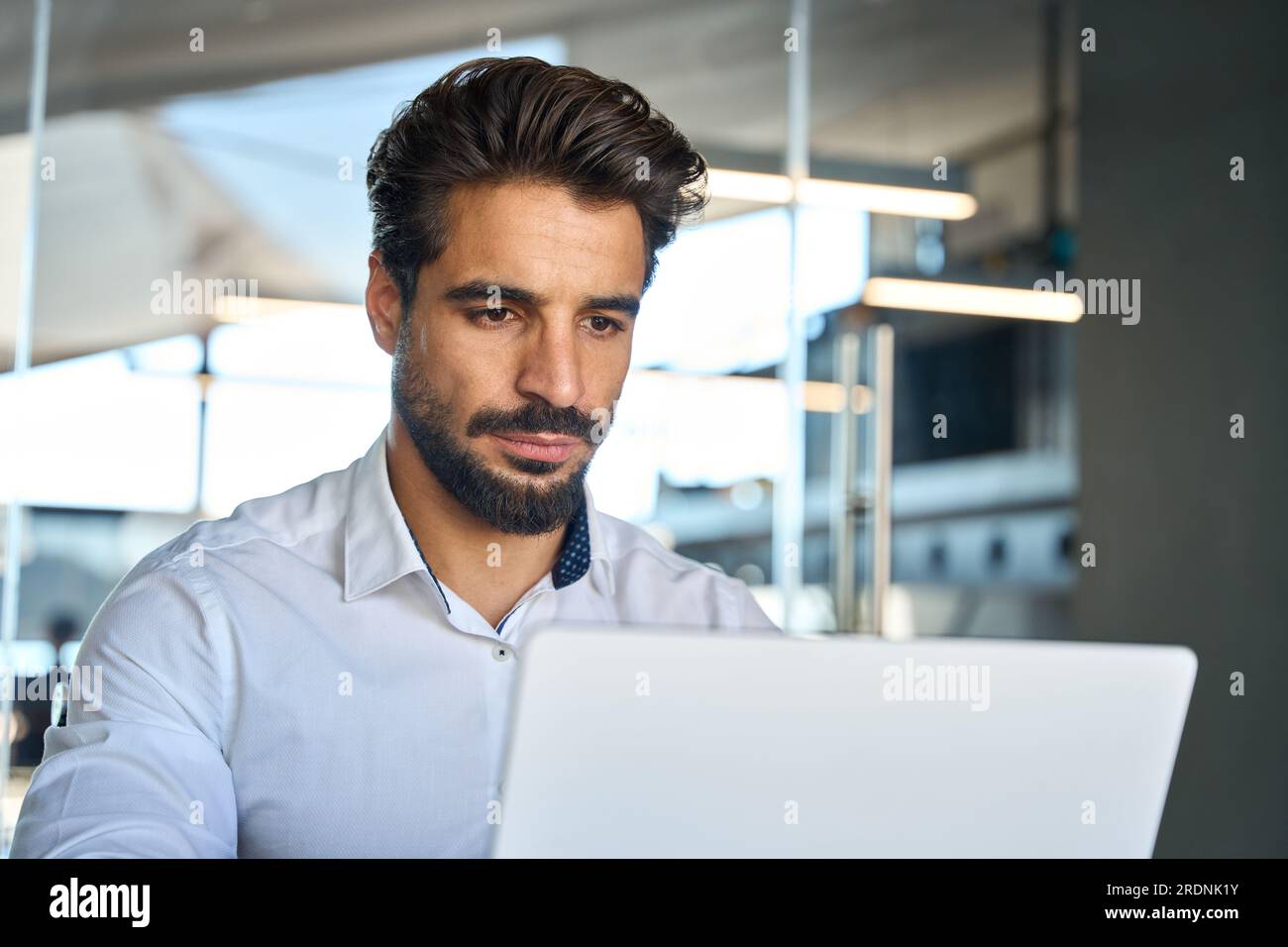 Busy young Latin business man looking at laptop using computer at work ...