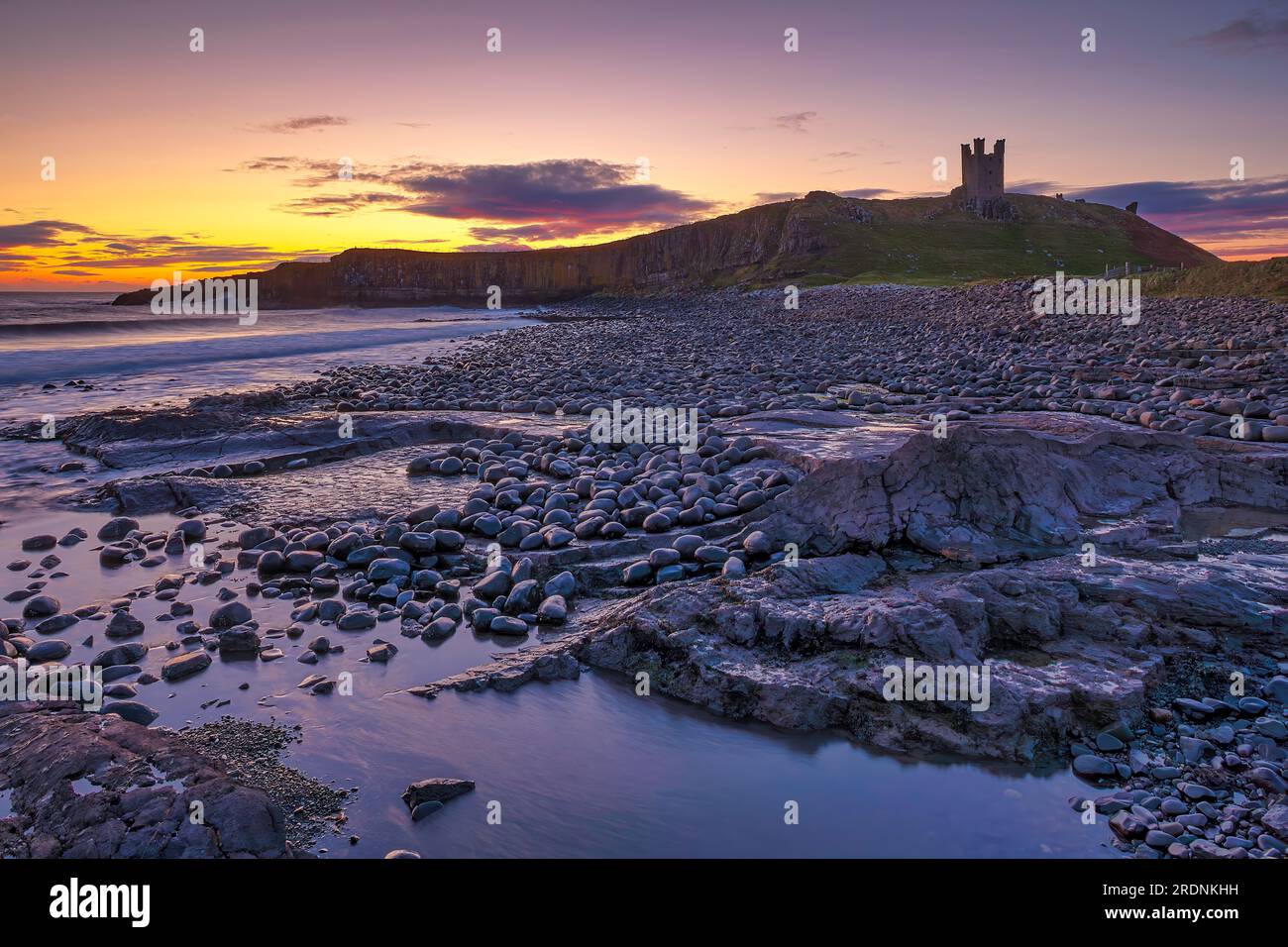 Sunrise at Dunstanburgh Castle near Embleton in Northumberland looking towards Craster, England ...