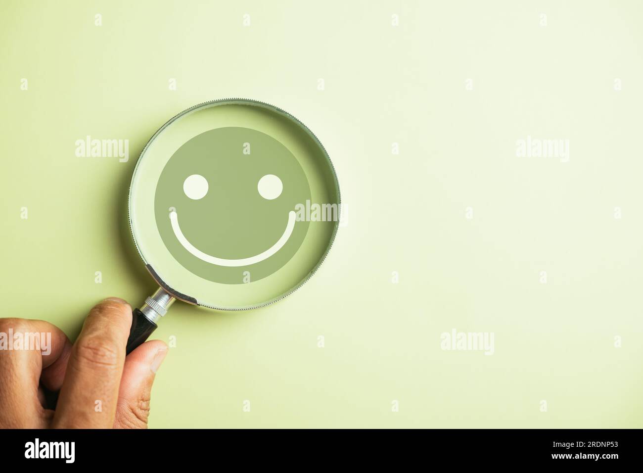 Magnifier in hand focuses on selected happy smiley face icon Stock ...