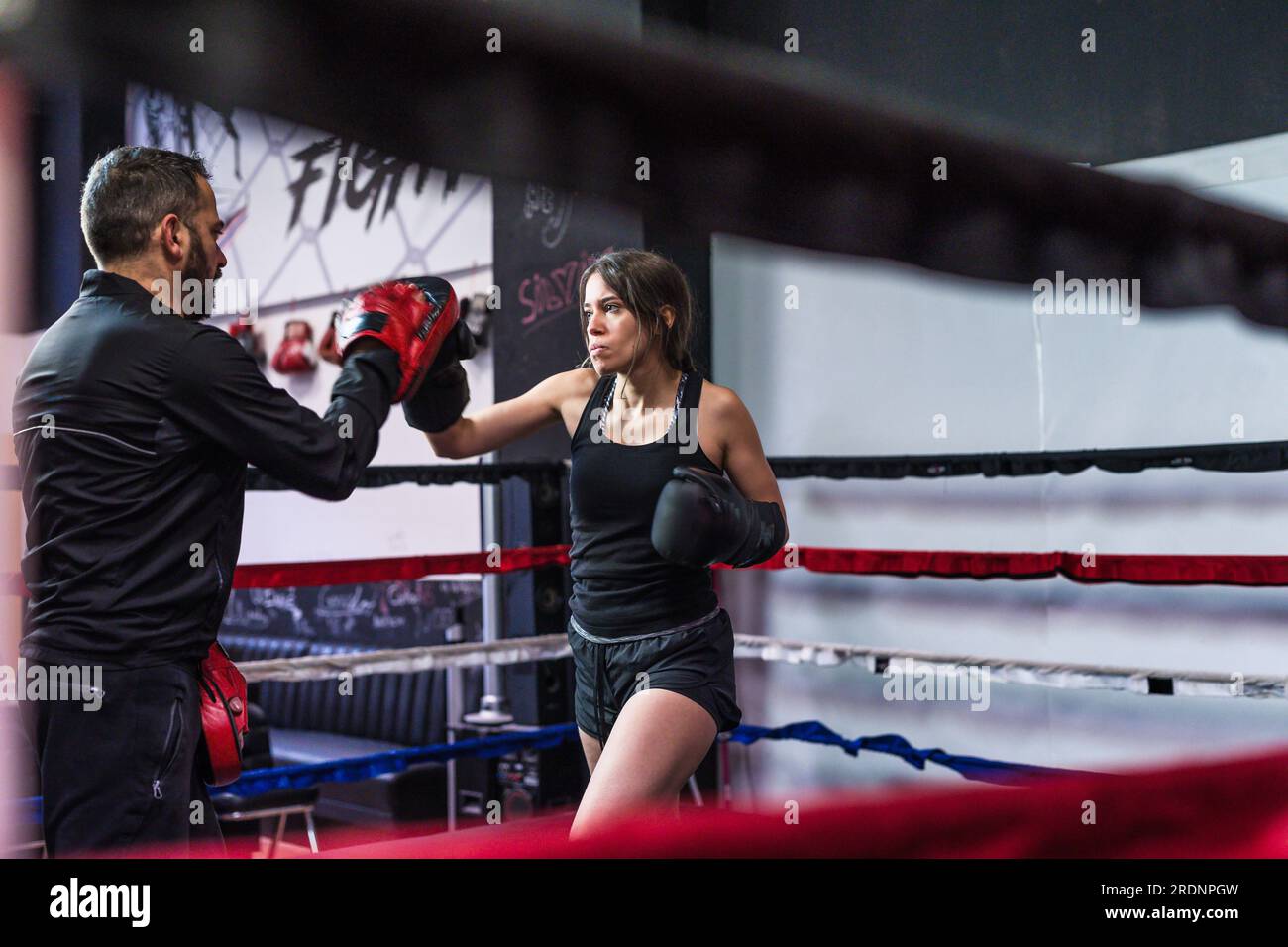 K1 50s instructor at gym. Hispanic woman punch action with gloves ...