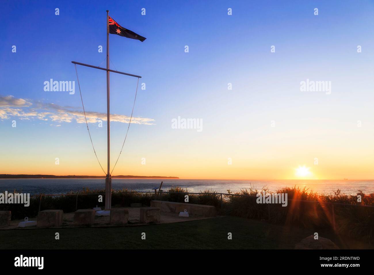 Waving national australian flag facing rising sun over Pacific ocean ...