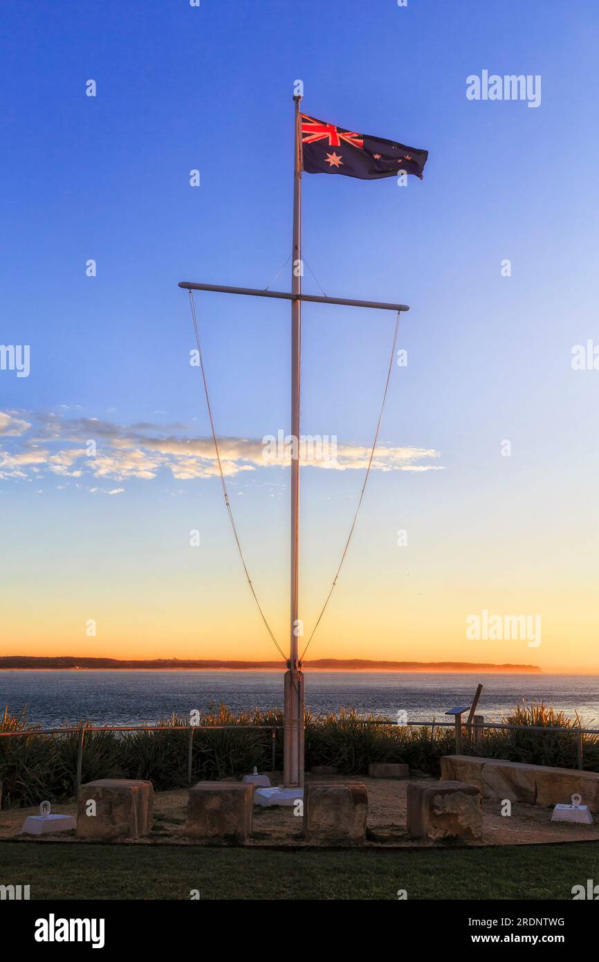 Waving national australian flag facing rising sun over Pacific ocean at ...
