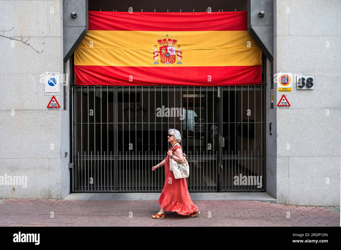Madrid, Spain. 21st July, 2023. A woman walks past a Spanish flag for ...