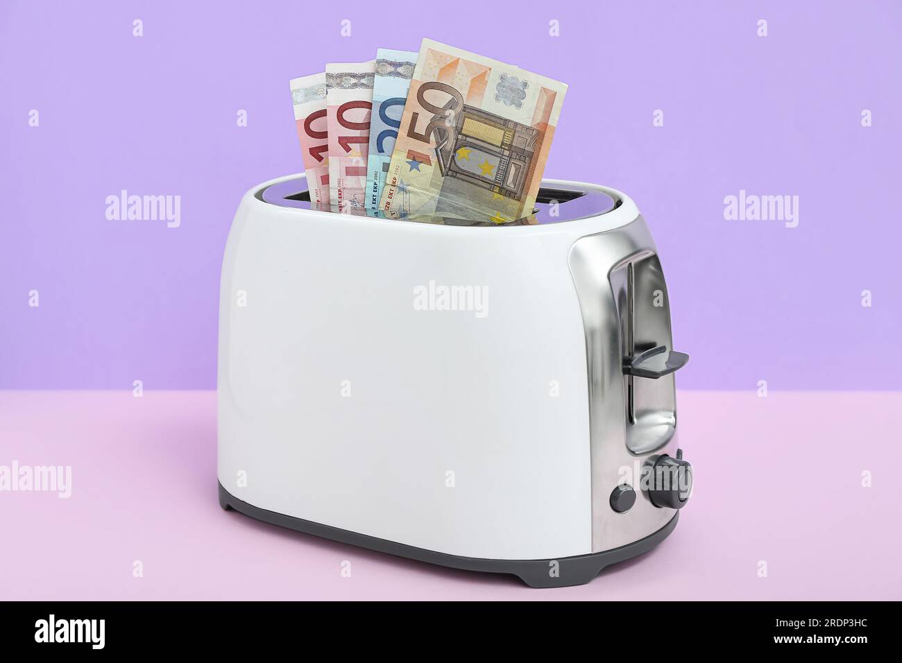 Toaster with euro banknotes on table near lilac wall Stock Photo - Alamy
