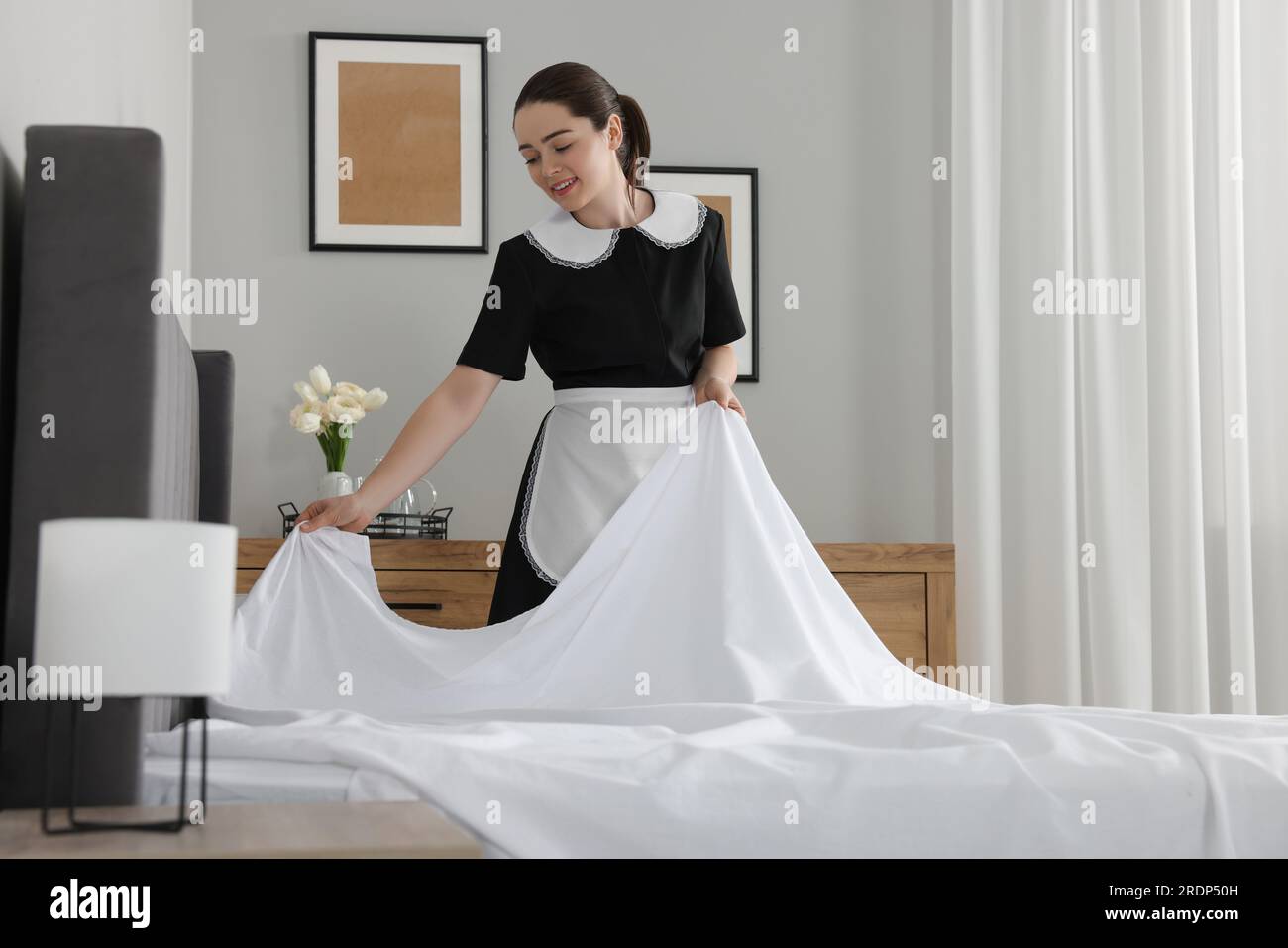 Young maid making bed in hotel room Stock Photo - Alamy