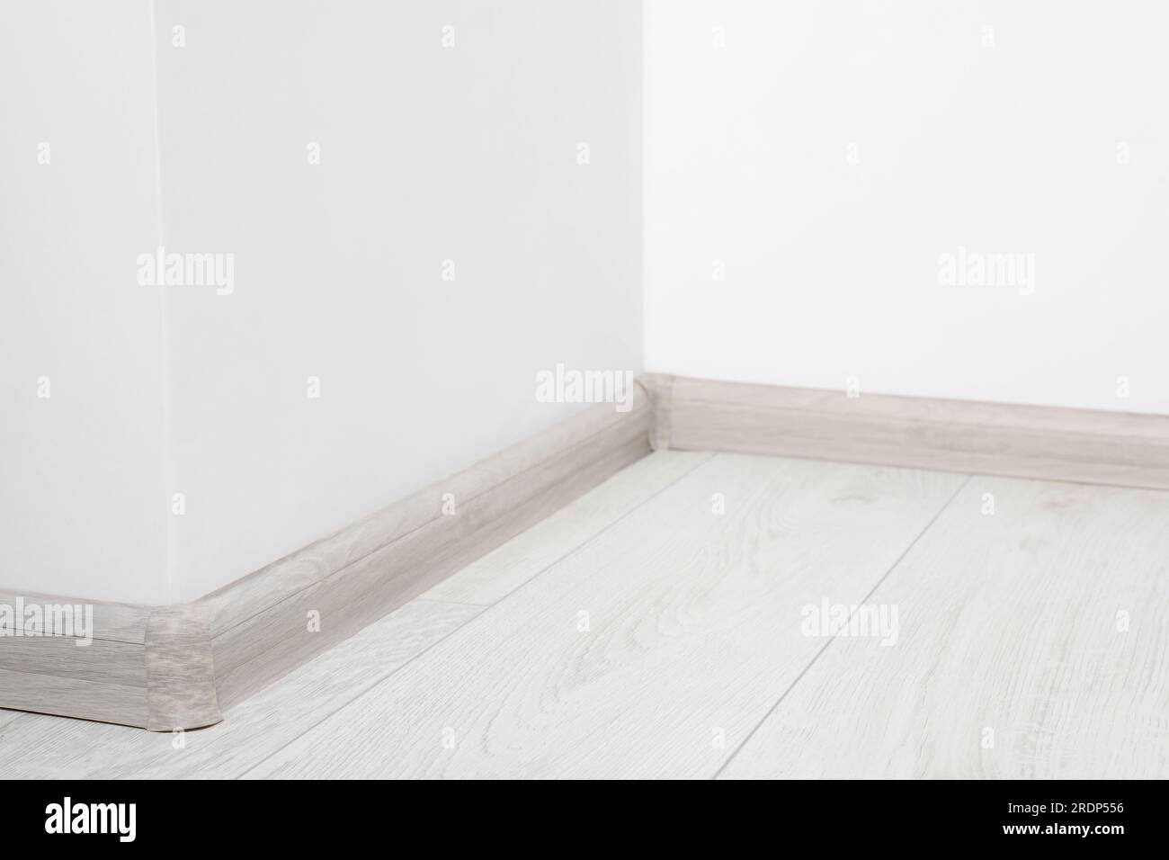 Wooden plinth with connectors on laminated floor near white wall ...