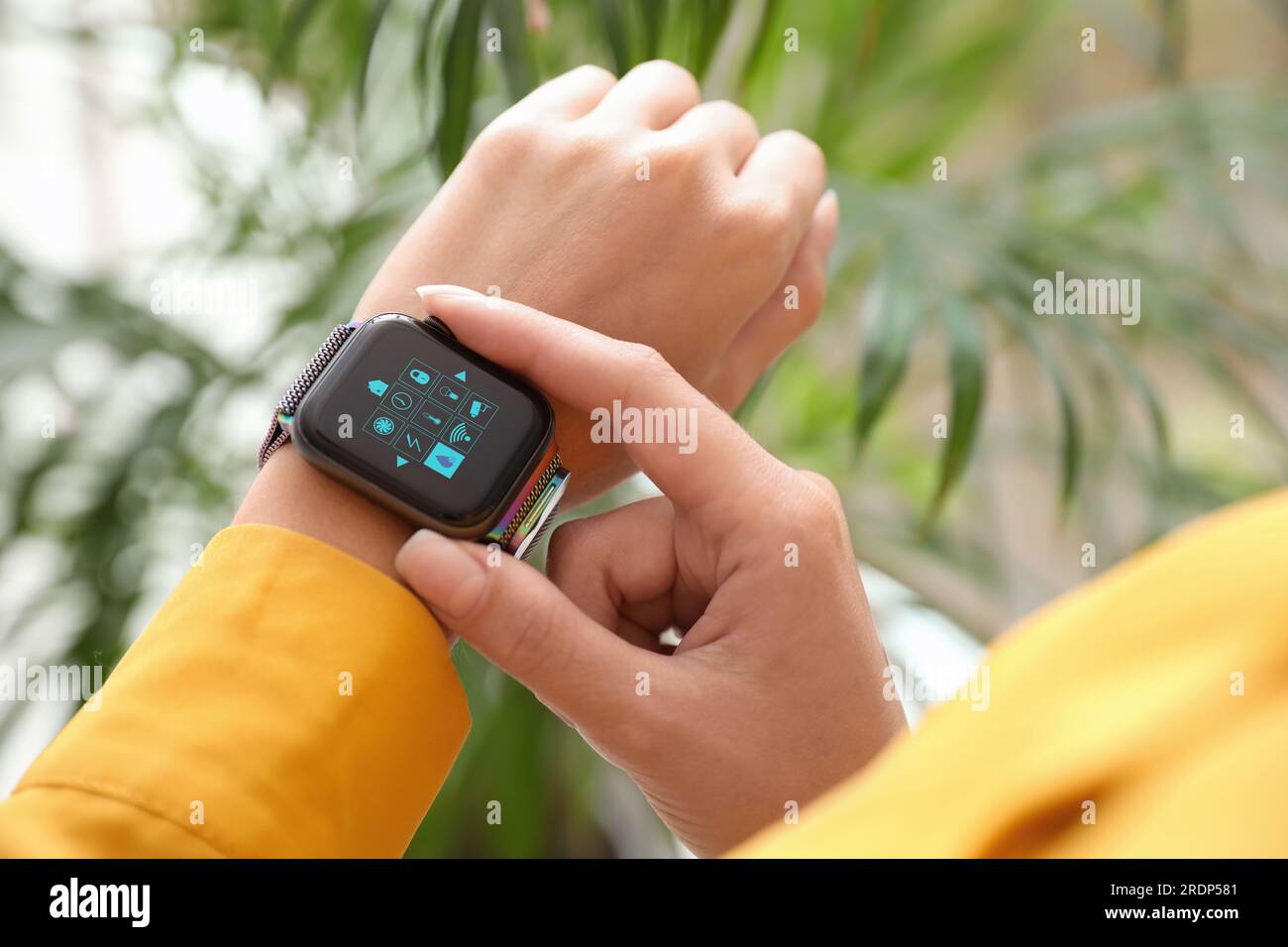 Woman setting smart home control system via smartwatch indoors, closeup ...