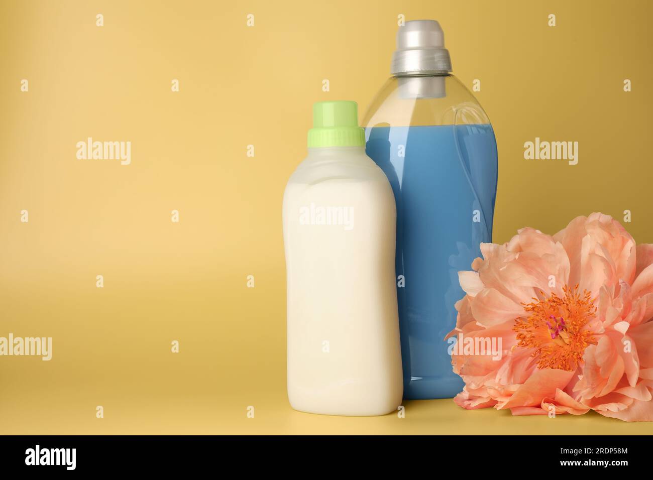 Bottles of fabric softener and beautiful flower on pale yellow ...