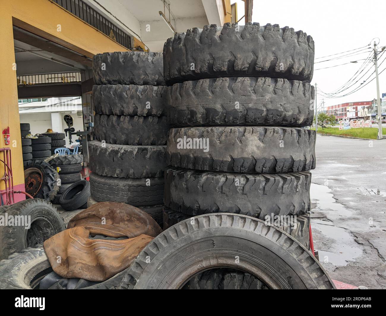 A pile of different types of used tires is placed outside a tire shop ...