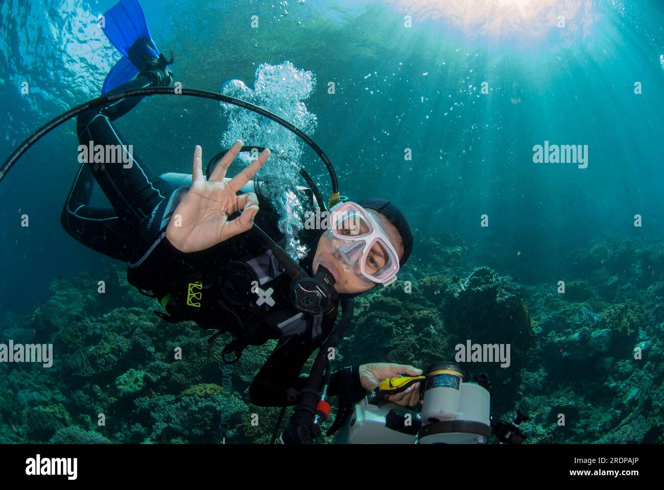 Female diver, model released, with camera signalling with sun in ...