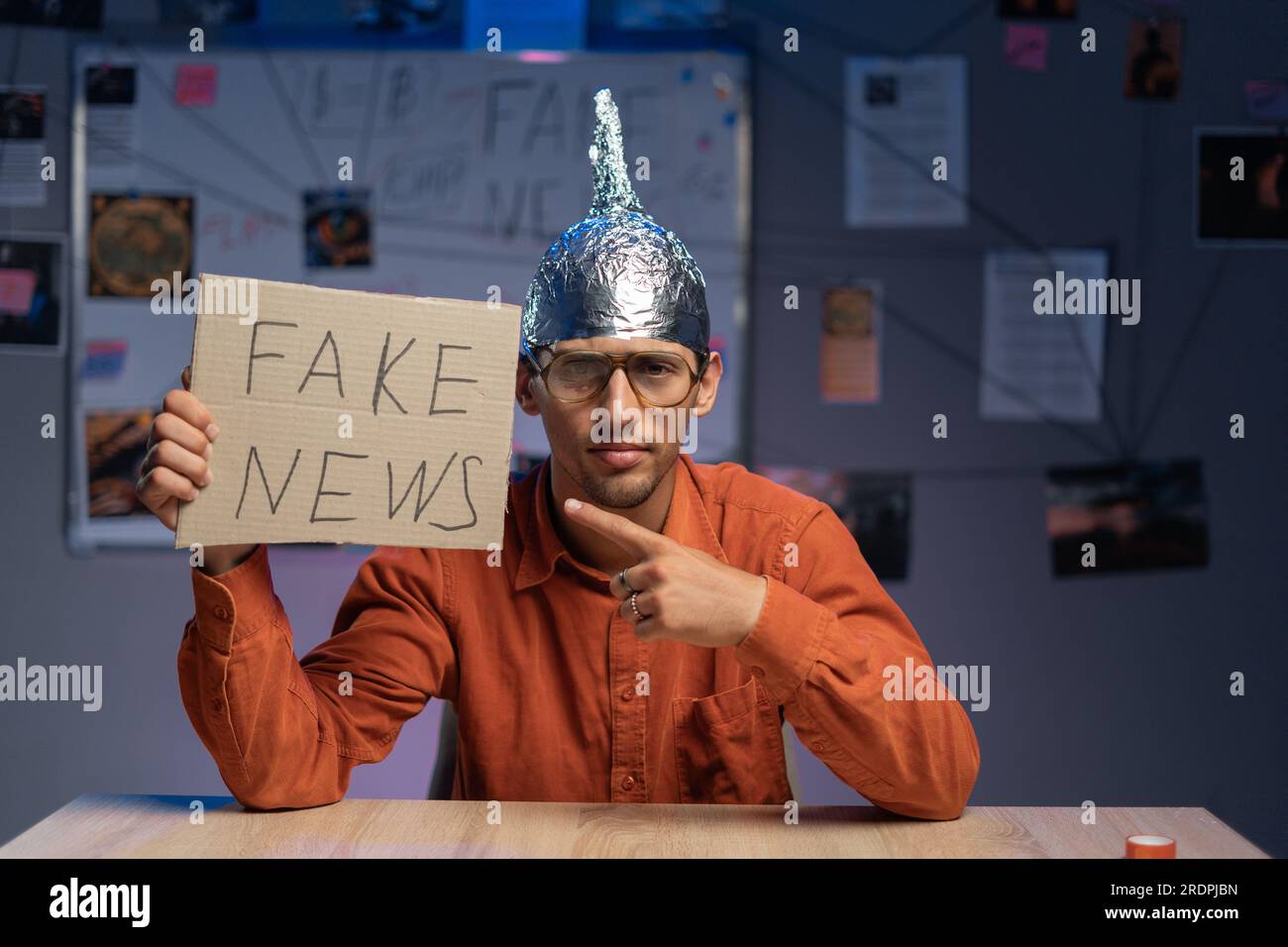Strange man in a protective foil cap and glasses holding banner with ...