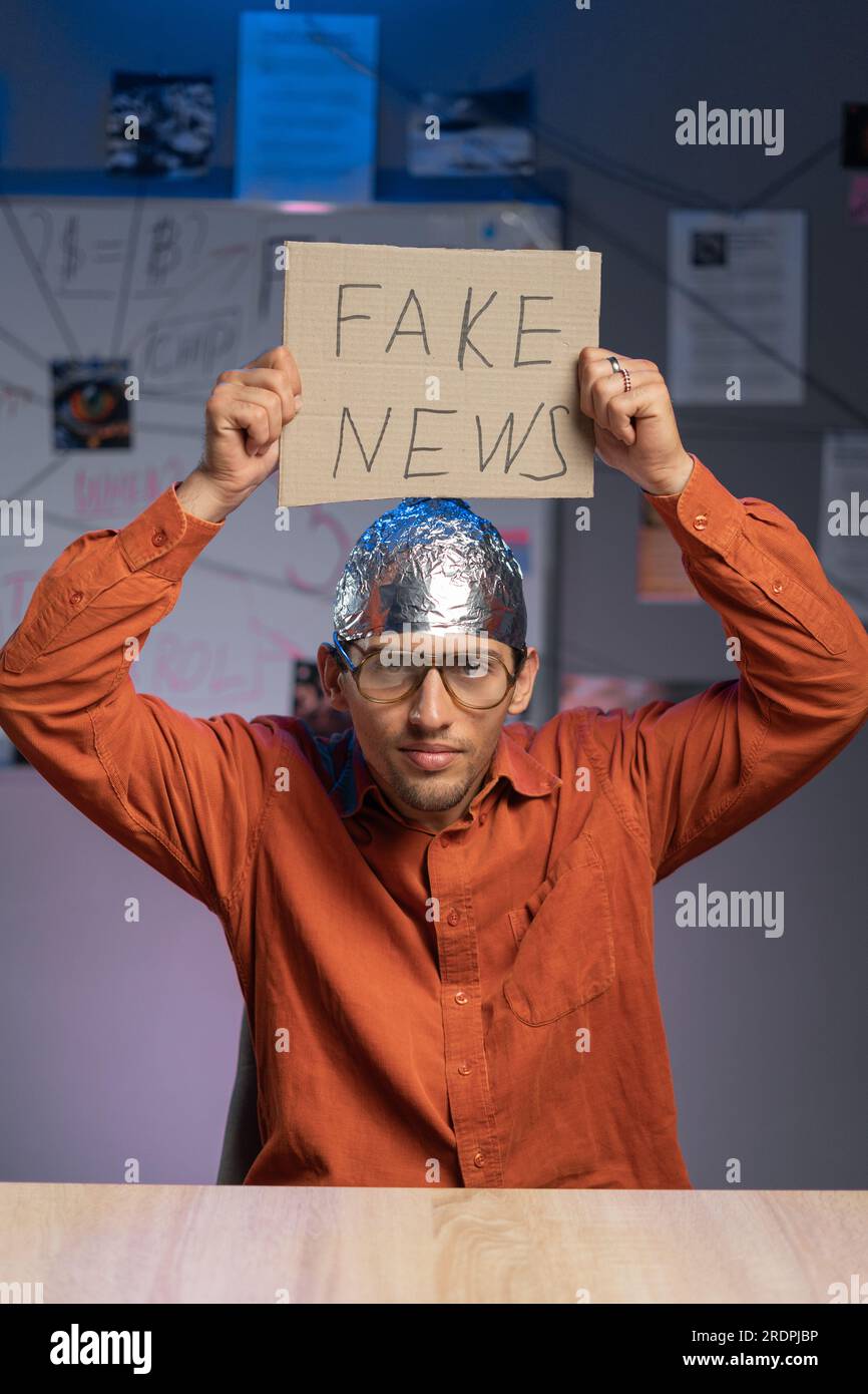 Strange man in a protective foil cap and glasses holding banner with ...