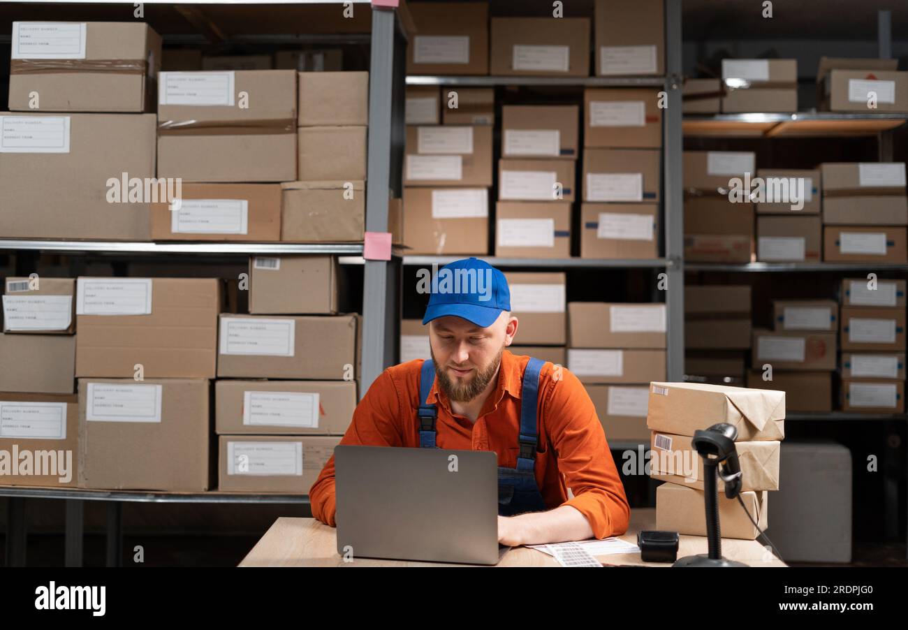 Worker manager checking on merchandise, working on laptop computer in ...