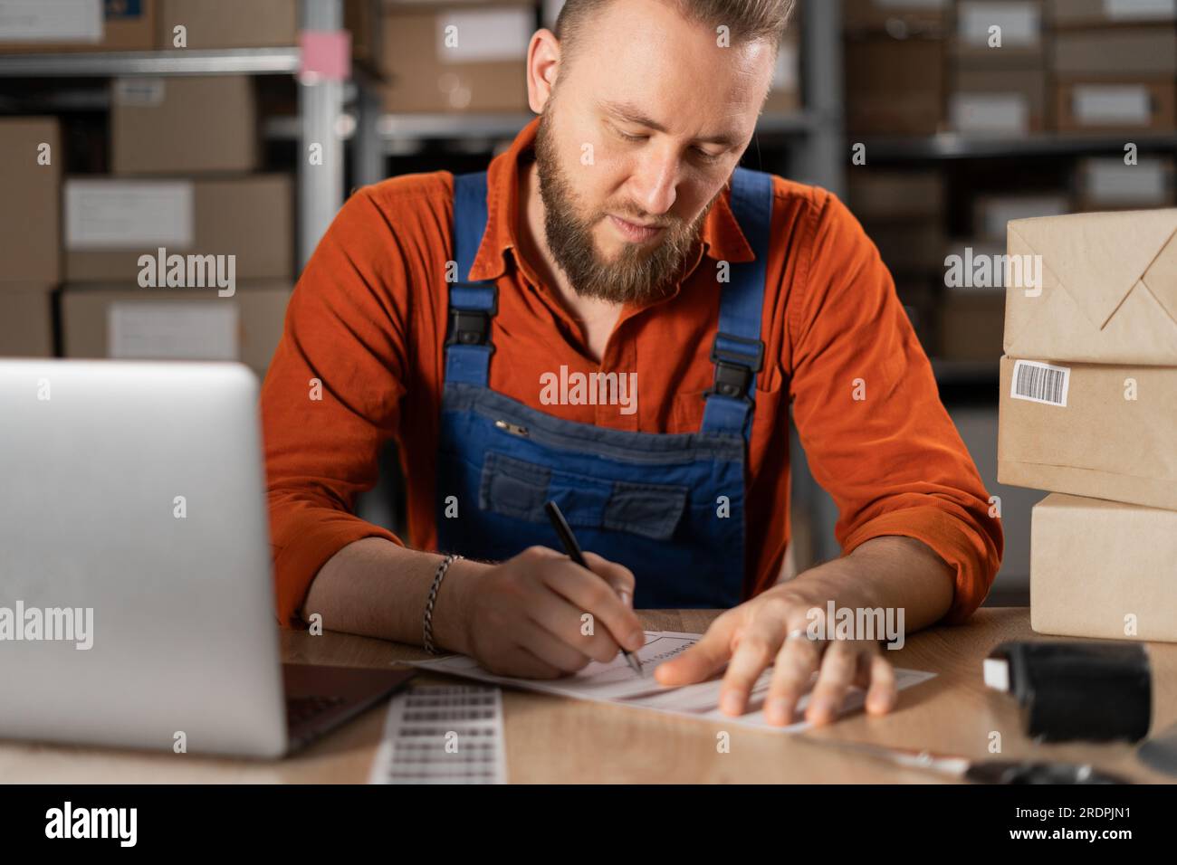 Small business owner working in storeroom with laptop, preparing order ...
