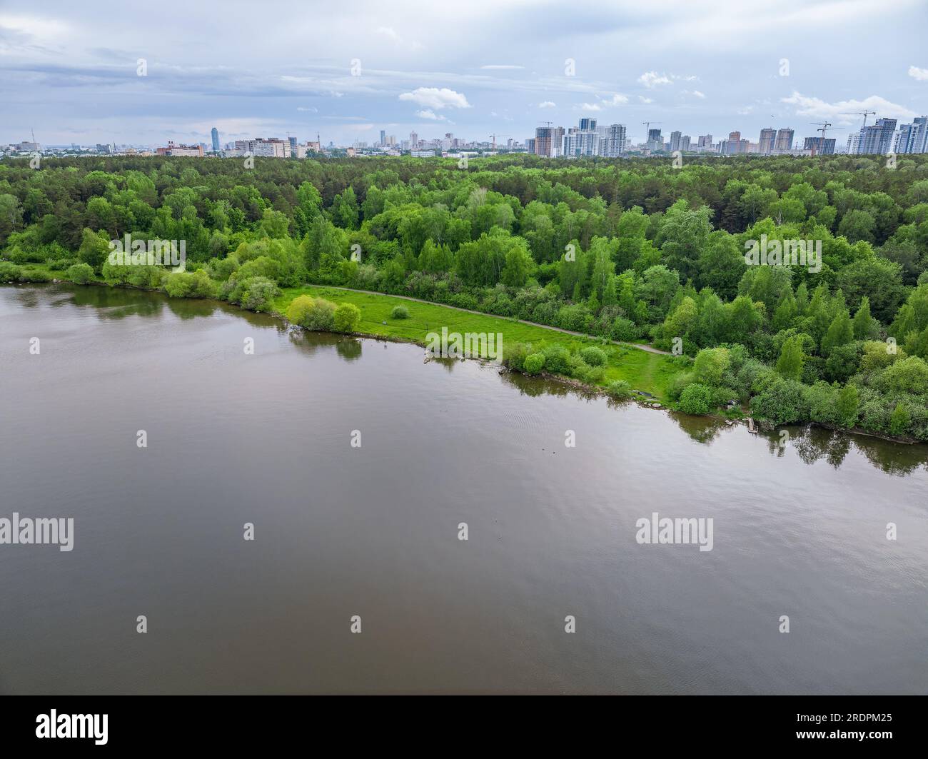 Big lake with green shores in bright sun light and city on horizon ...