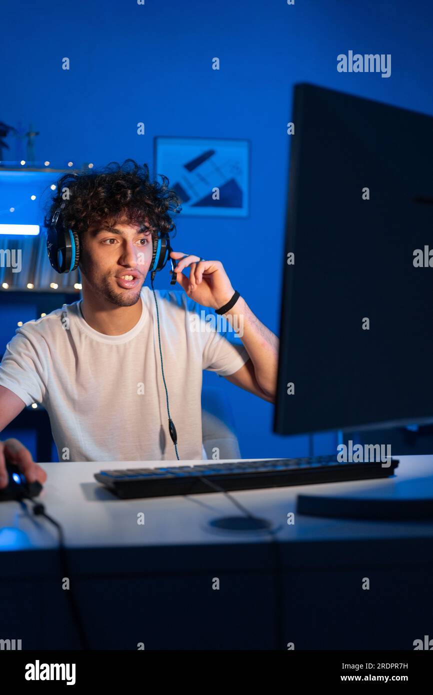 Positive arabic guy gamer streams game on computer and looks smiling at ...