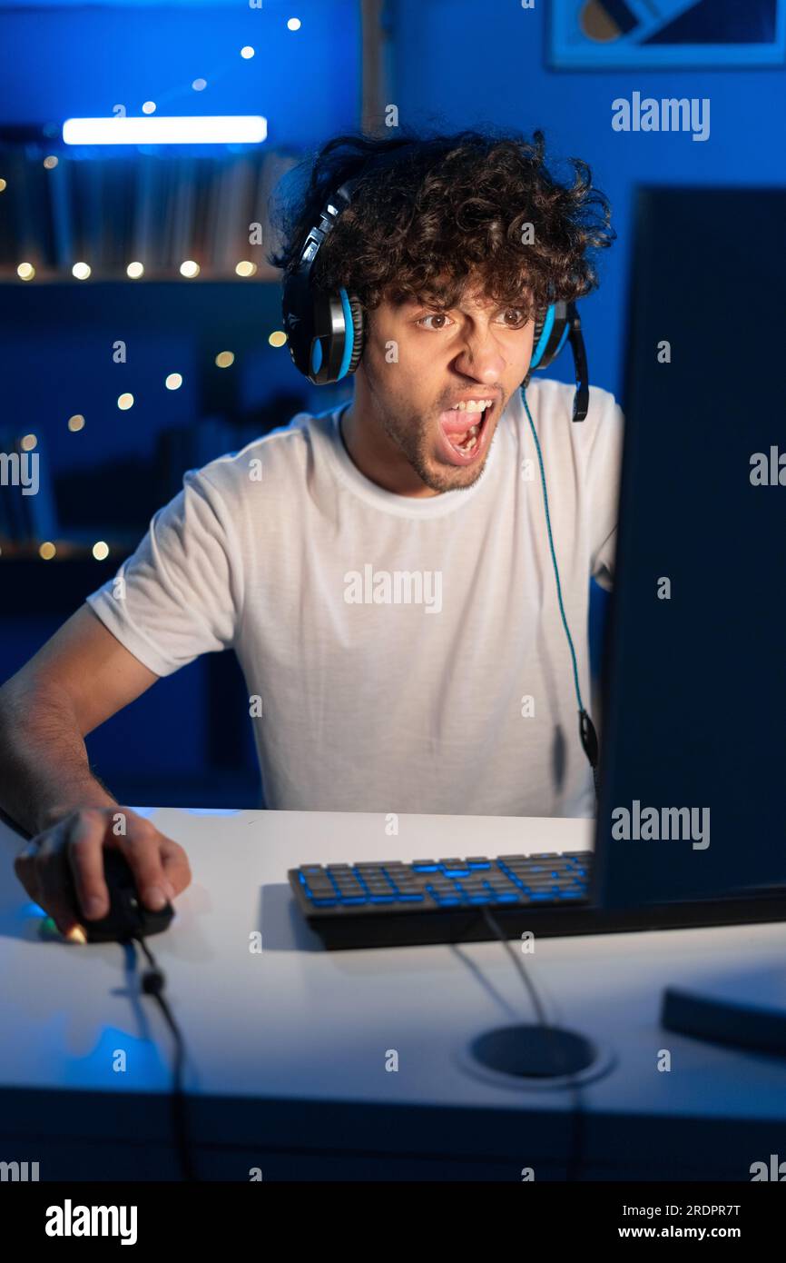 Young arabic gamer wearing headphones playing video game on personal ...