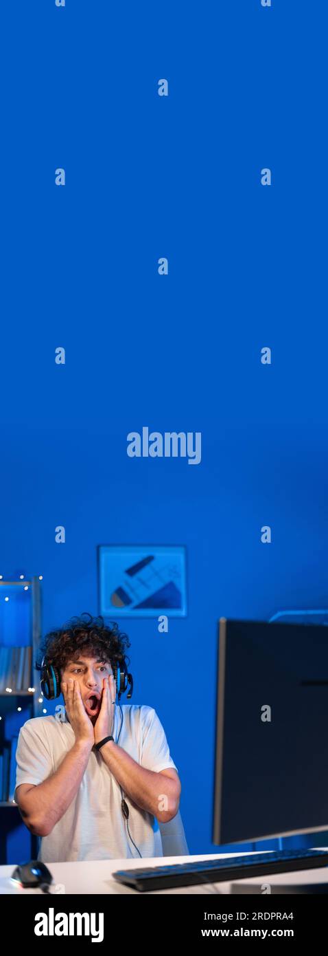 Shocked arabic gamer in headset at night near computer staring at ...