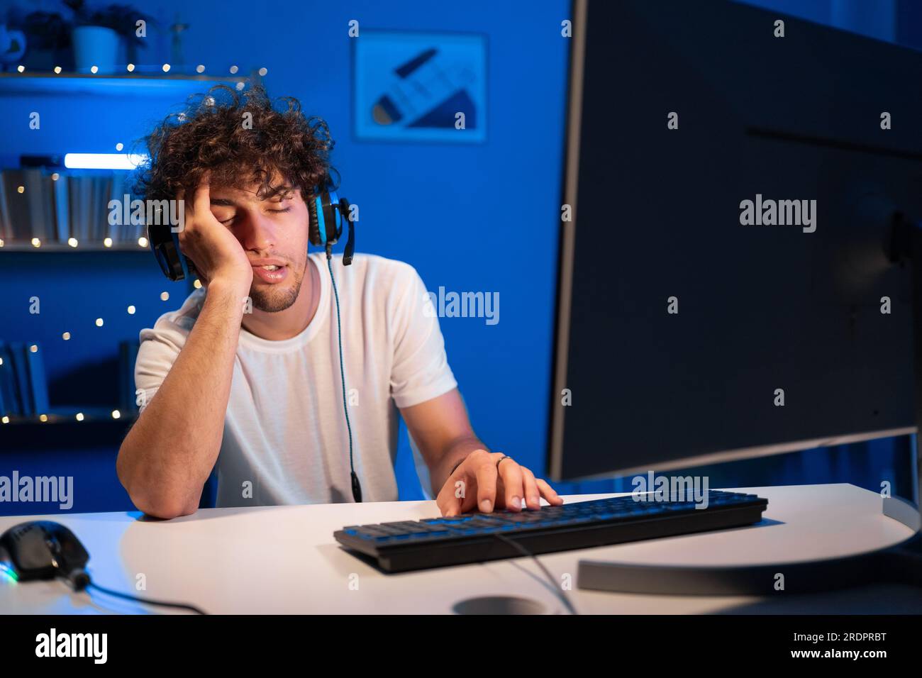 Arabic man gamer in a headset sleeps in a gaming chair at night near ...