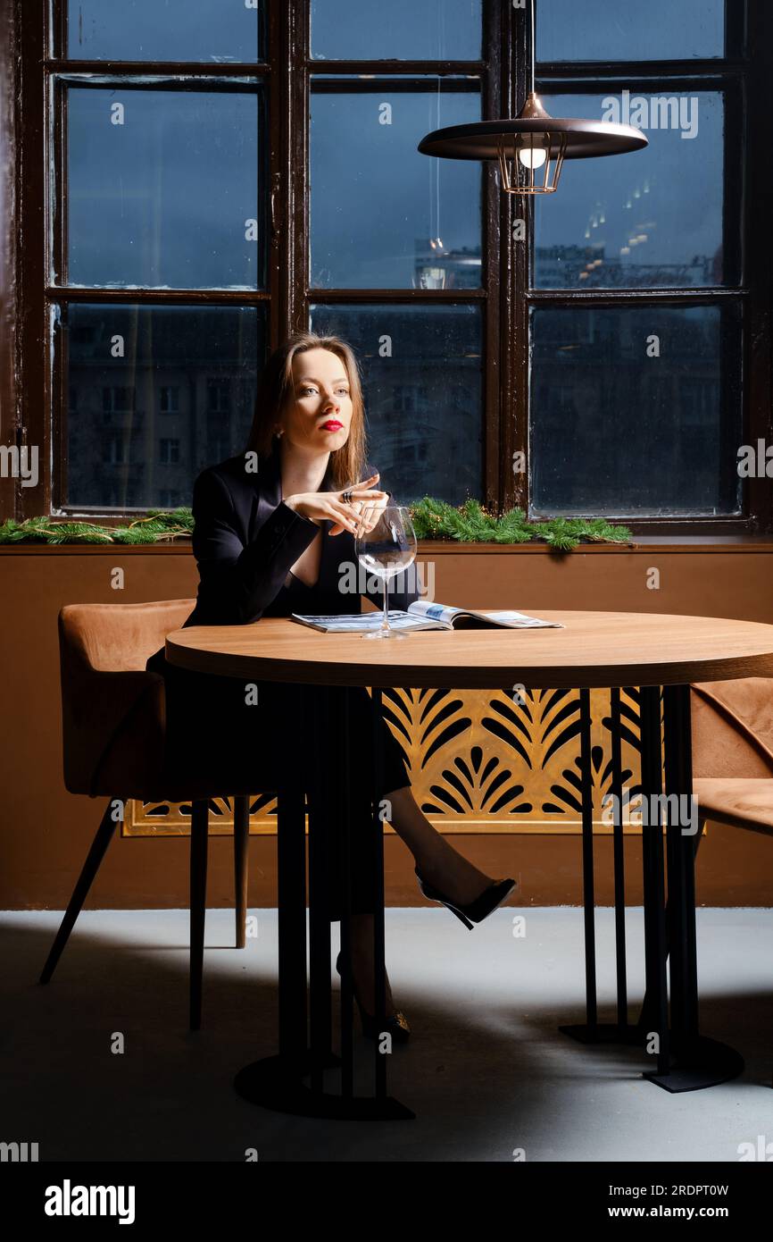 Lonely sad woman in pantsuit sitting behind empty table in cafe and ...