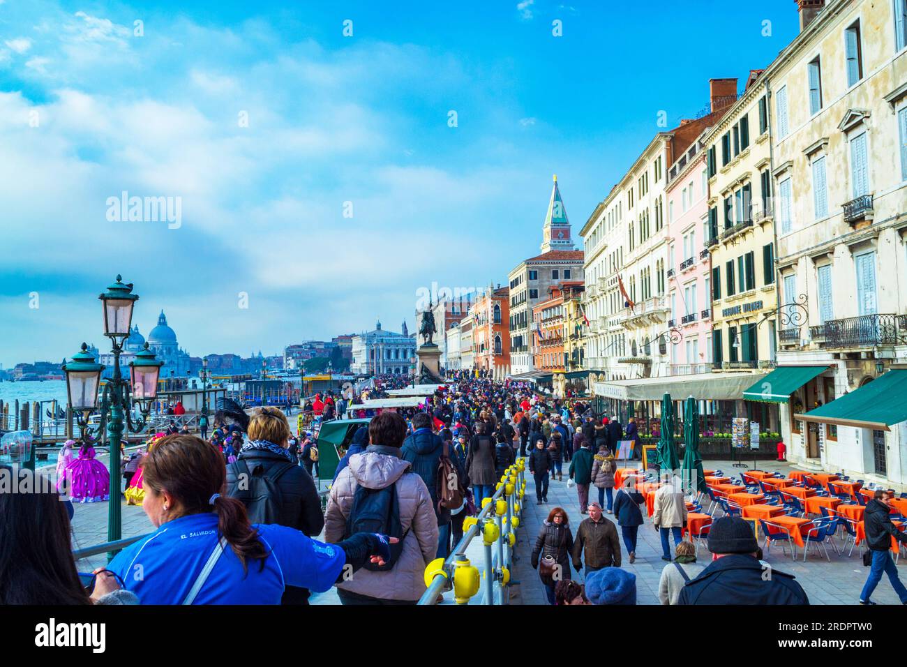 crowds of tourists and masquerade costumed people walking back and ...