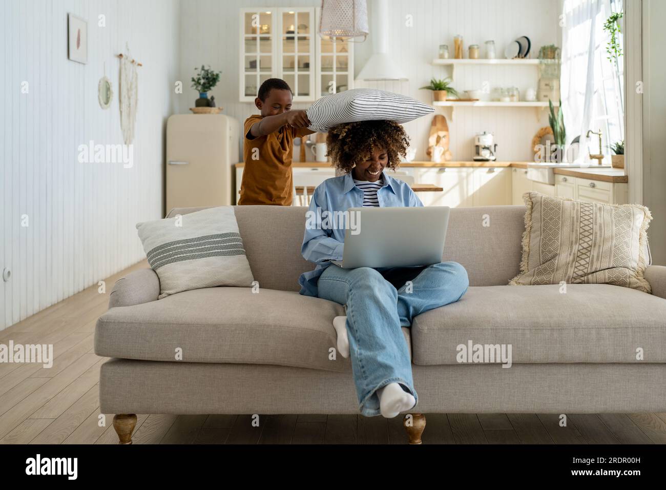 Content black child boy fun attack with pillow to busy smiling mom ...