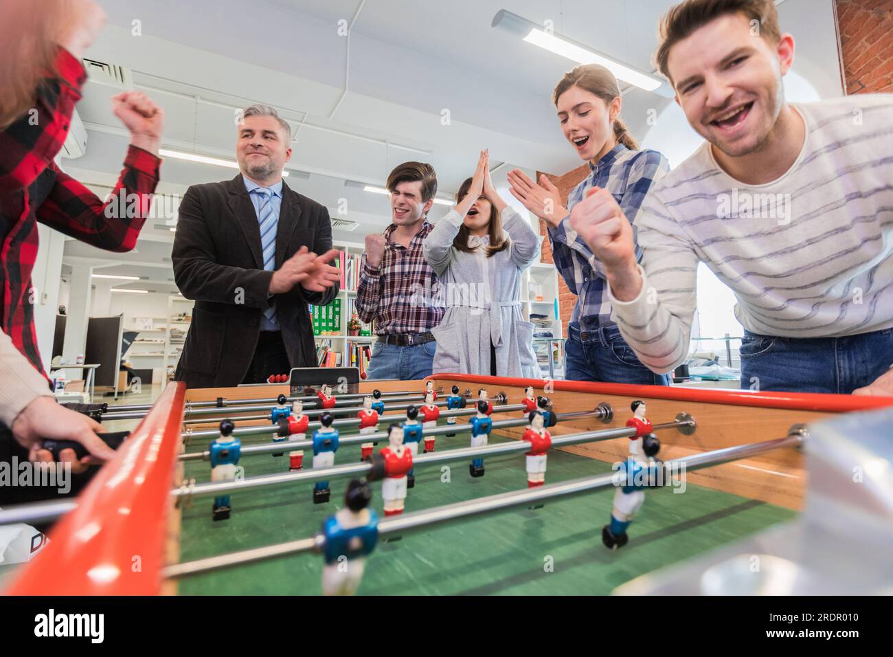 Employees playing table soccer indoor game in the office during break ...
