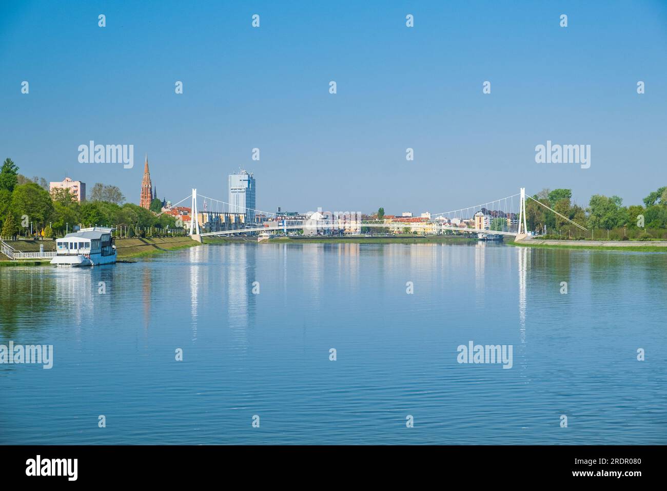 Pedestrian bridge over the Drava river and skyline of city of Osijek ...