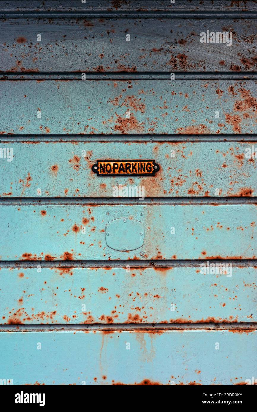 Blue rusty garage door with a no packing sign Stock Photo - Alamy