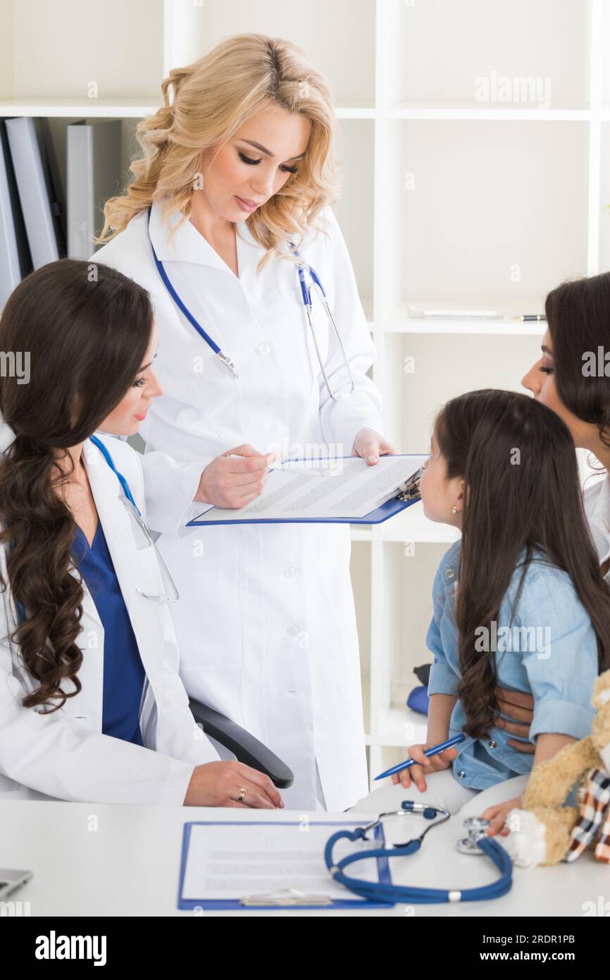 Young mother and girl in pediatrician office, doctor giving diagnosis ...