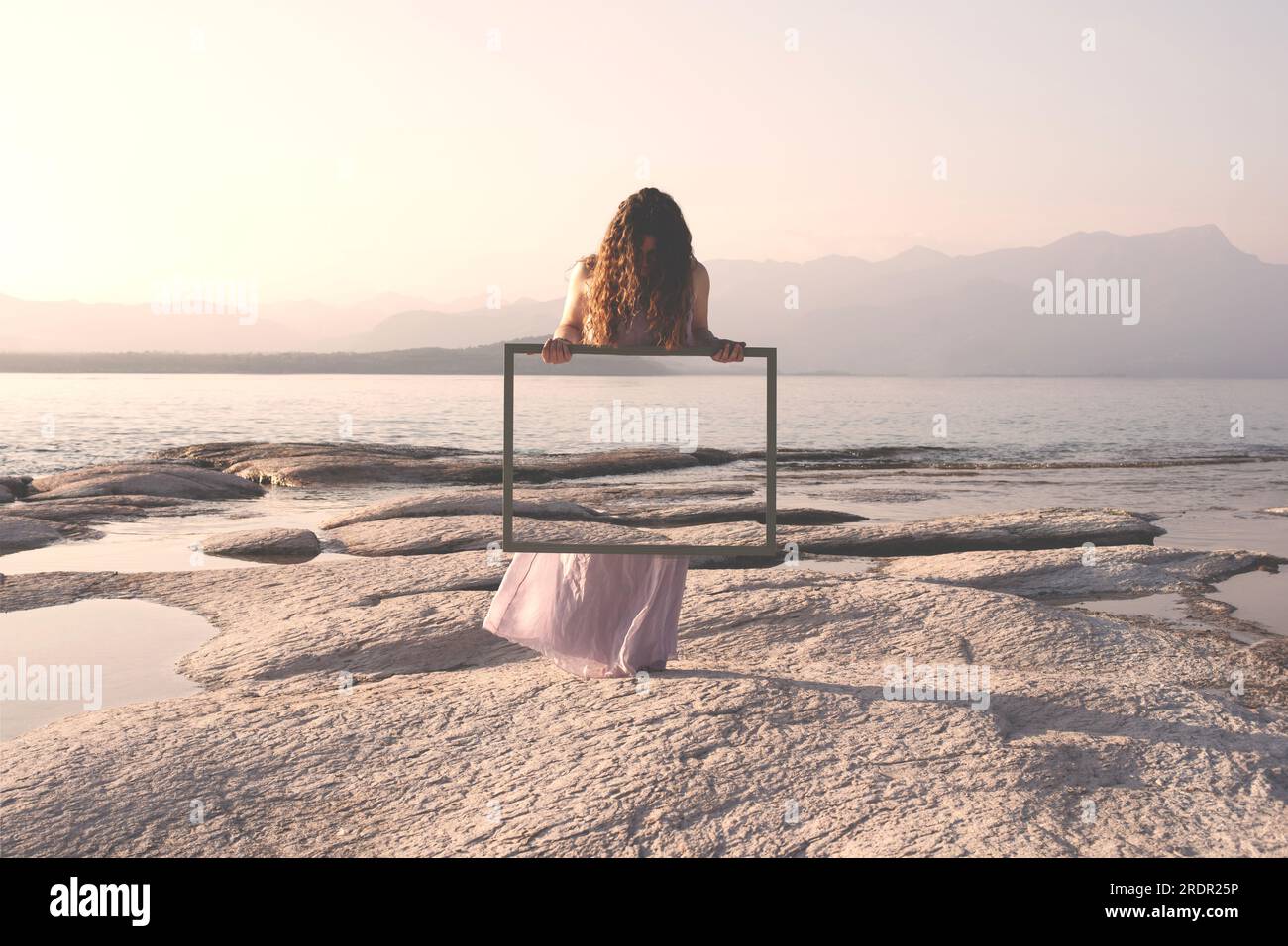 woman holding a frame that surreally reflects the landscape , concept ...