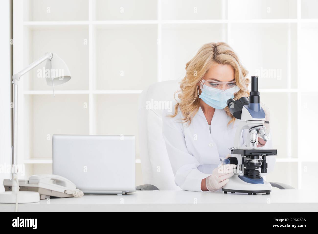 Female doctor looking through a microscope at medical clinic lab Stock ...