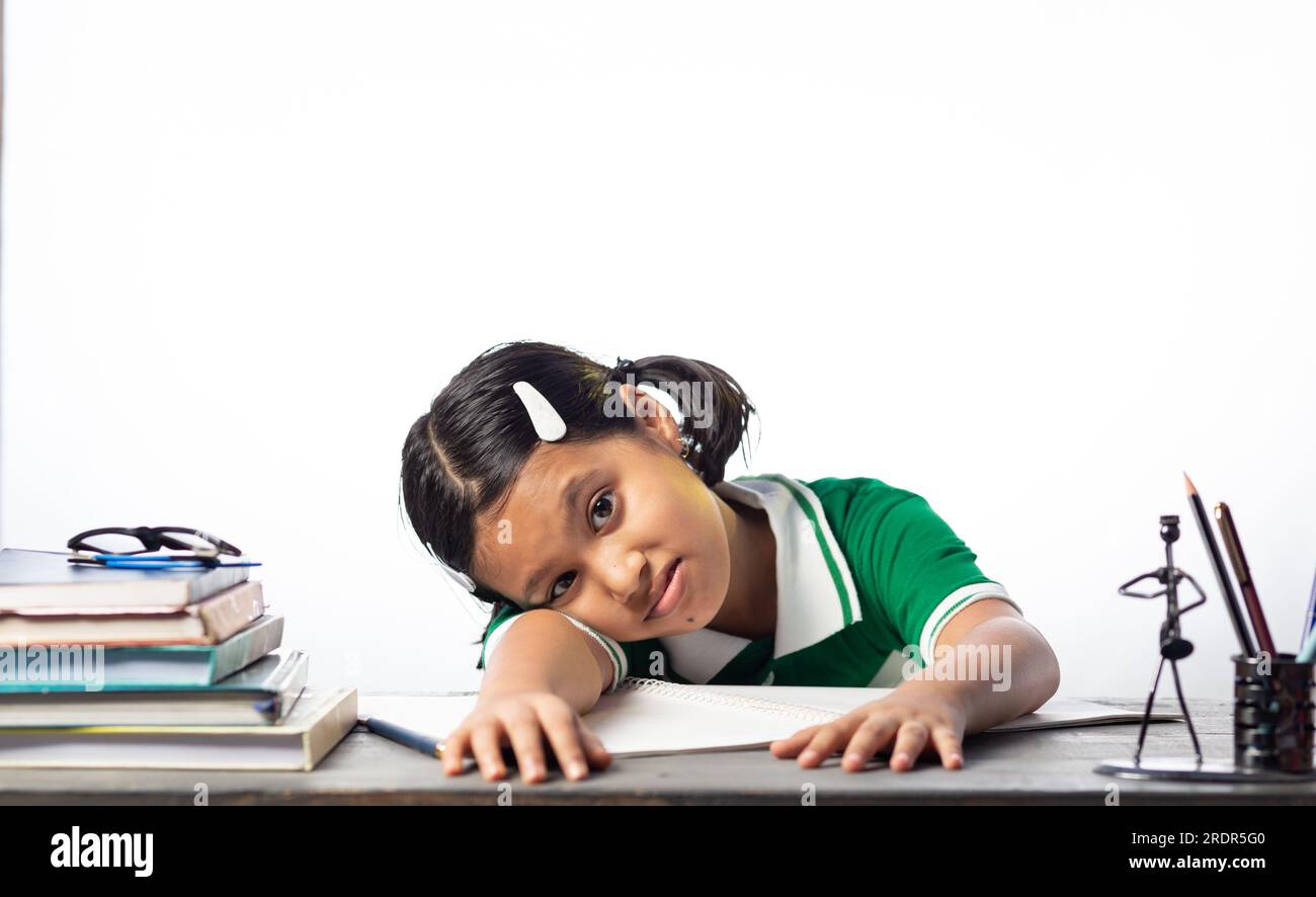 A pretty beautiful Indian schoolgirl child lying exhausted on study ...
