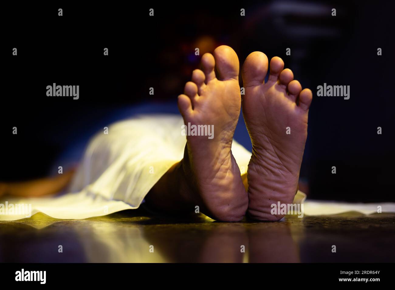 Feet of an Indian or Asian female dead body lying on floor in a dark ...