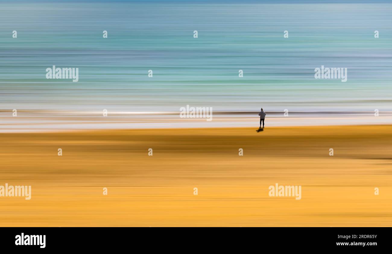 Distant, isolated person on a beach with background and foreground blur ...
