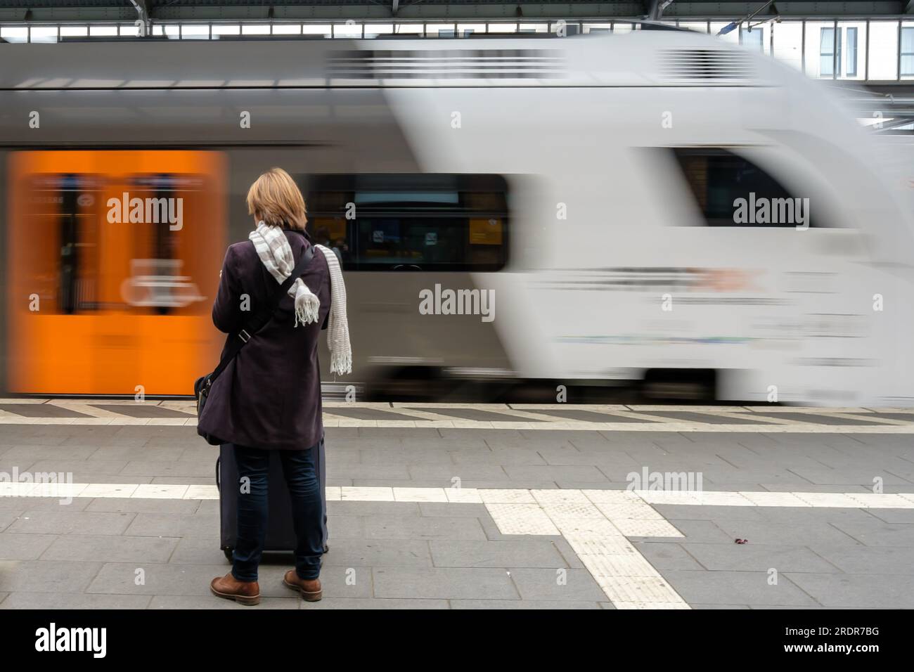 View of a single woman standing at the central rail station of Bonn ...