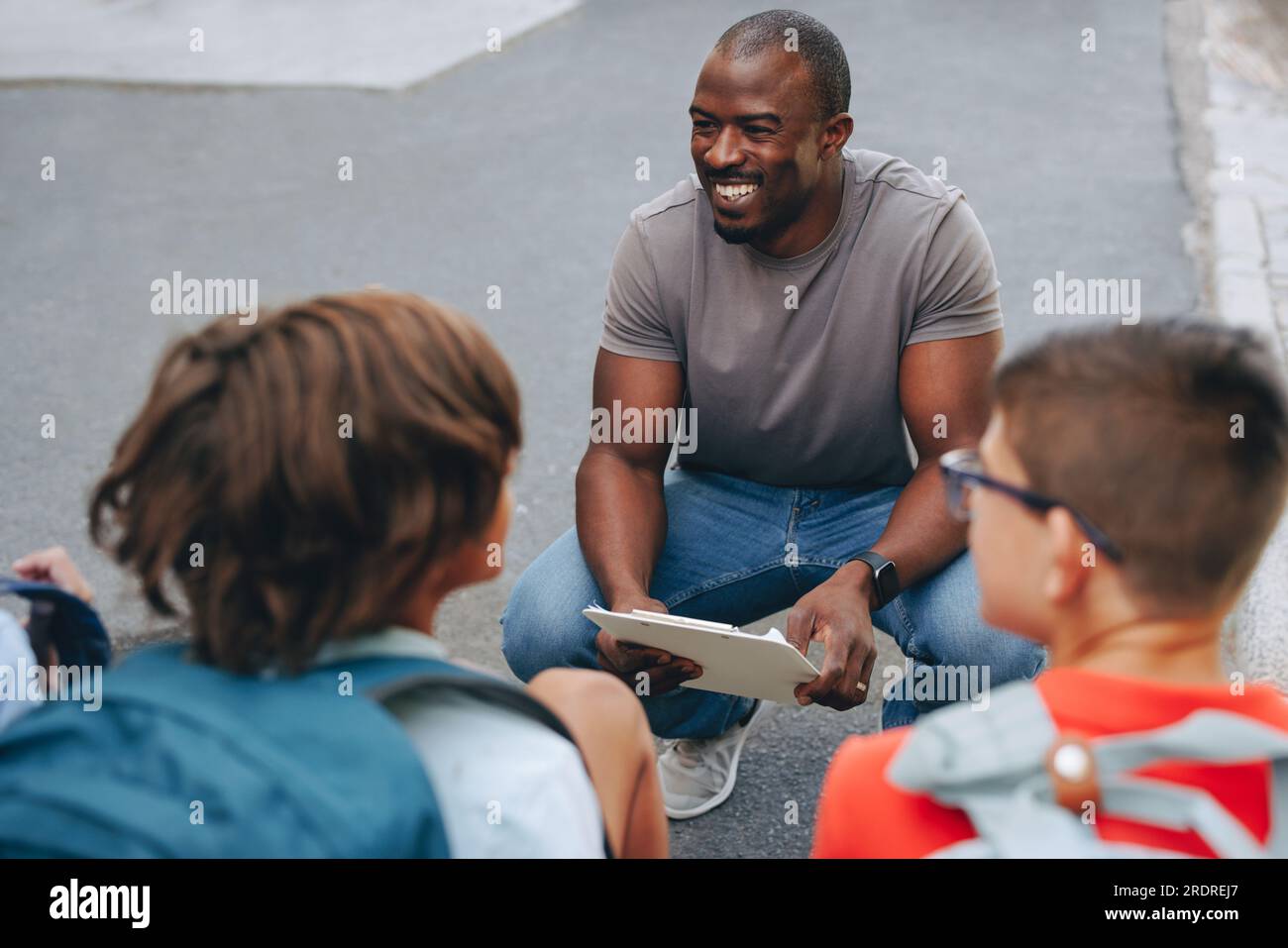 Happy primary school teacher having a pep talk with his students ...