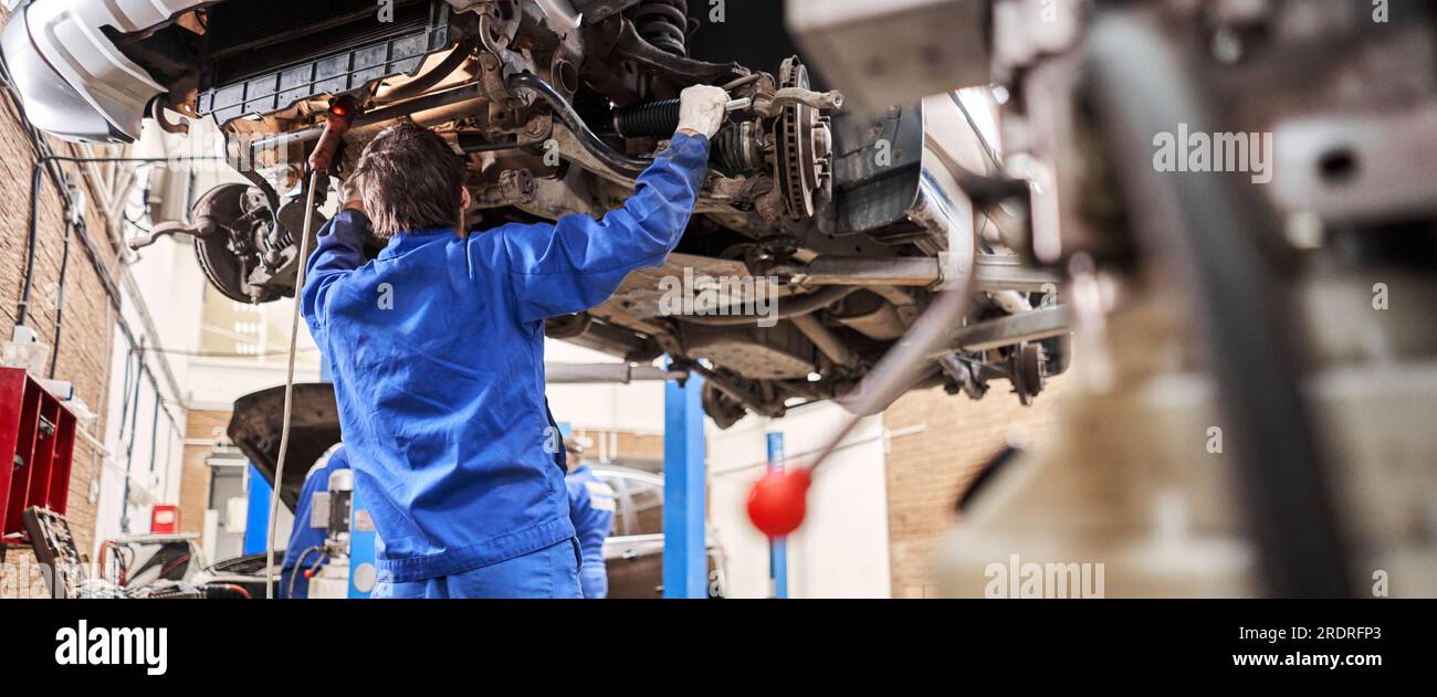 Car mechanic inspecting car steering rod and repair suspension detail ...