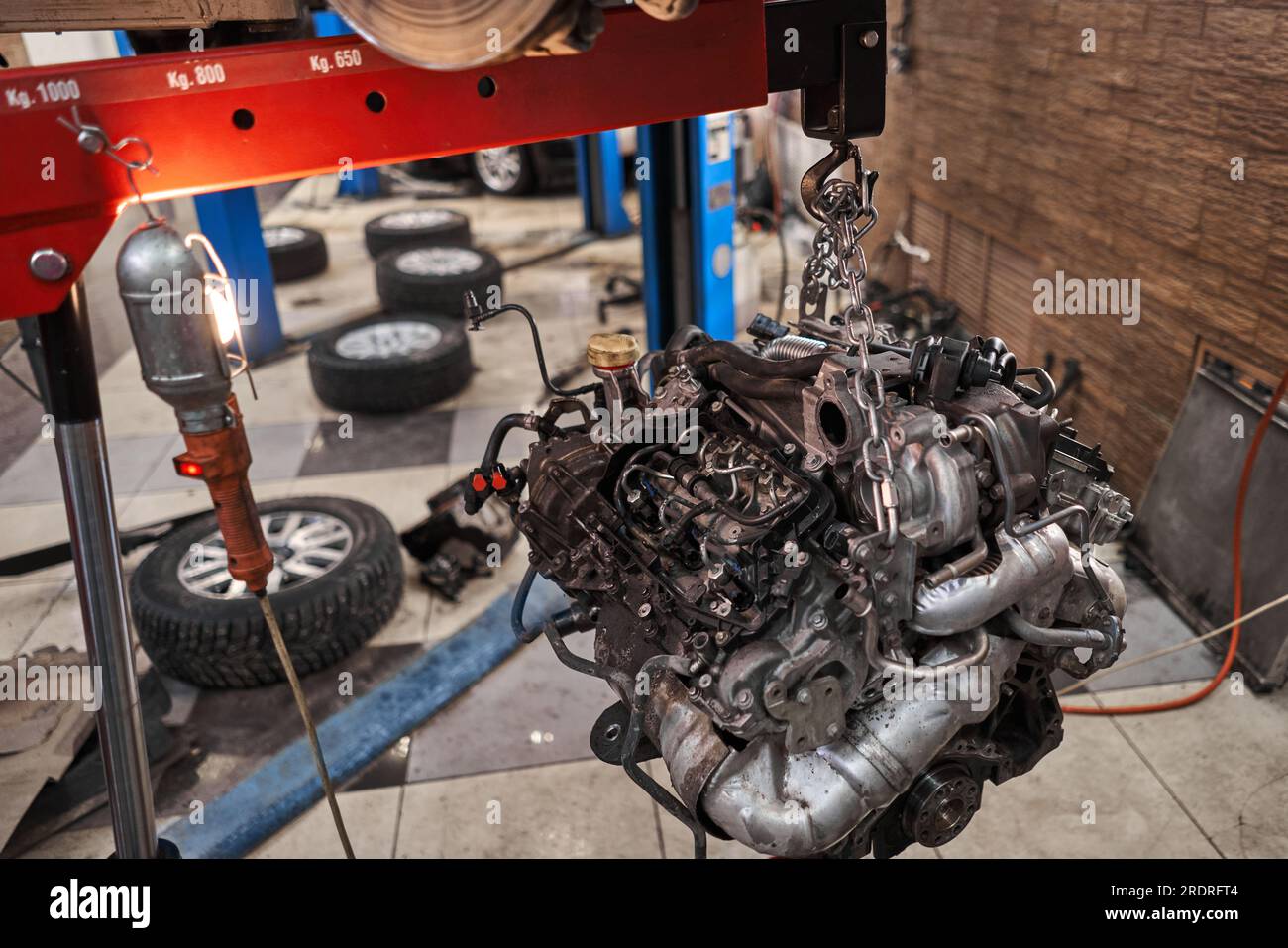 A car mechanic inspects the engine with a flashlight. Engine Block on a ...